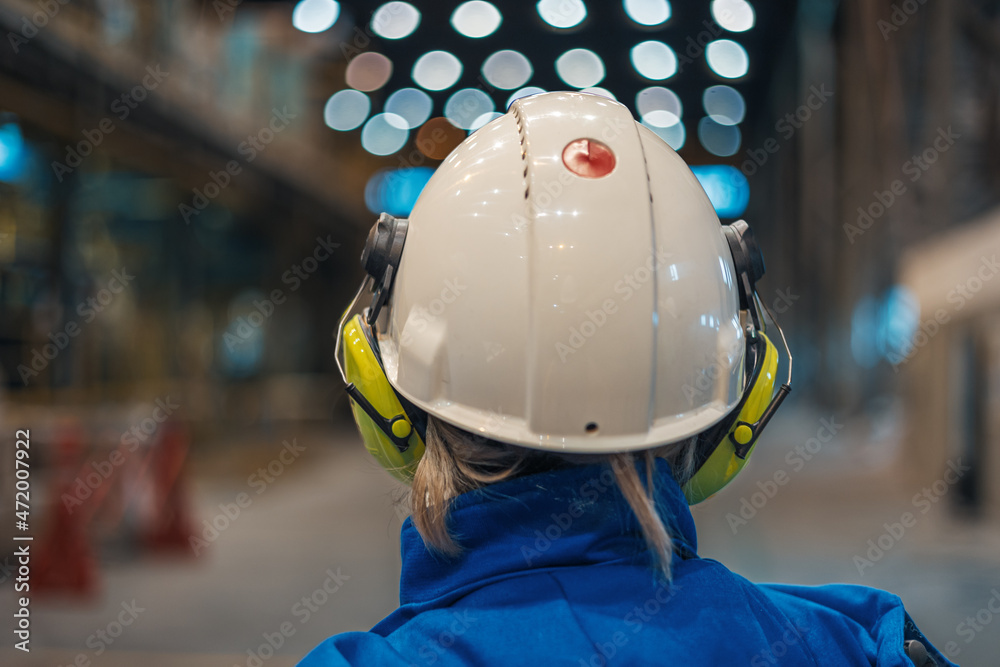 Back view of male worker wearing work vest and safety helmet while ...