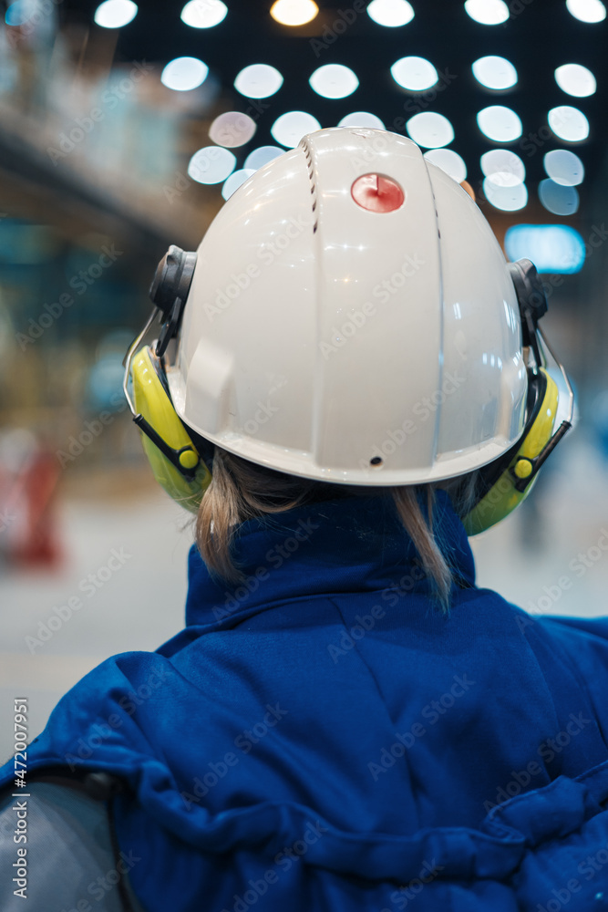 Back view of male worker wearing work vest and safety helmet while ...