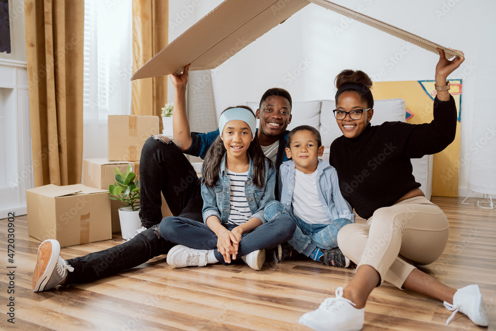 Family complete, parents with two children sitting on the floor ...