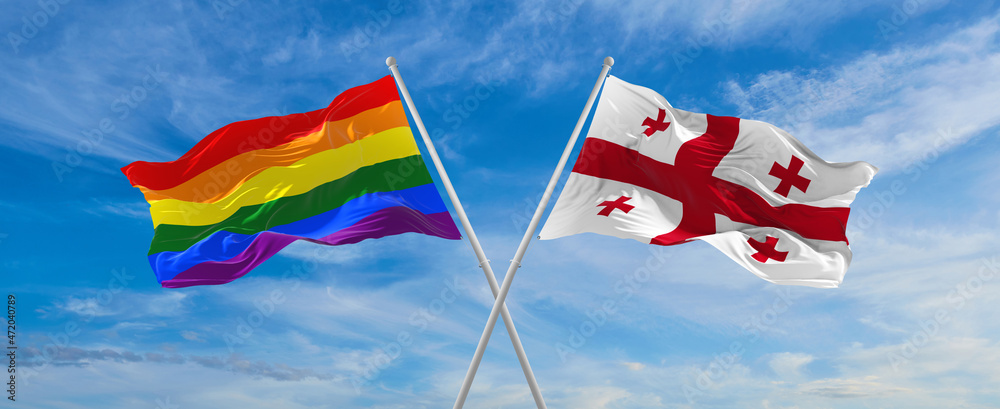 crossed flags of lgbt and Georgia flag waving in the wind at cloudy sky ...