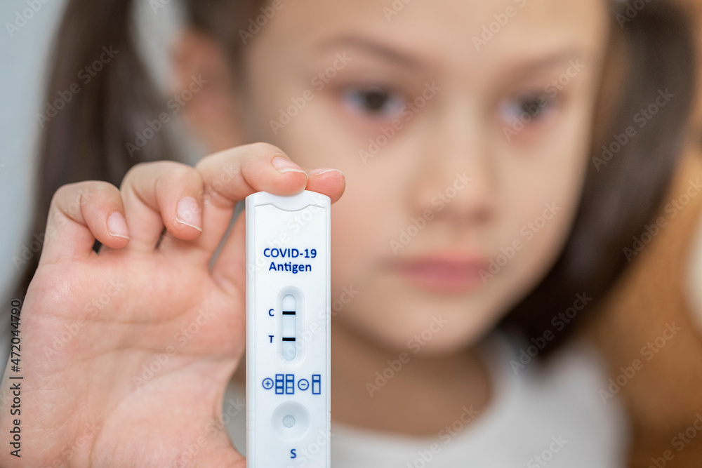 Sad girl holding positive COVID-19 antigen test Stock Photo | Adobe Stock