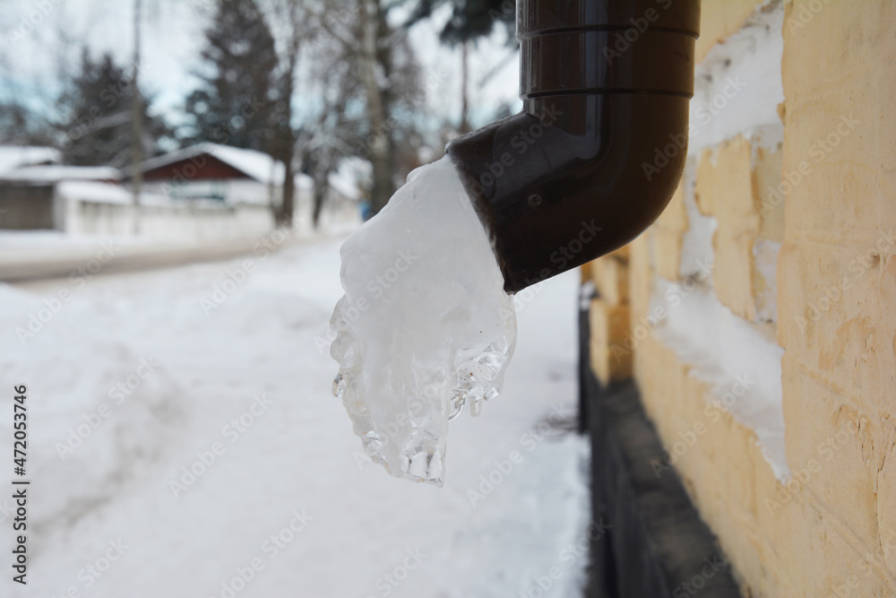 A frozen downpipe, downspout of a rain gutter system. Ice or frozen ...
