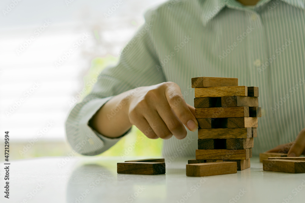 Young woman's hand pulling wooden blocks, hand-painted tower safety ...