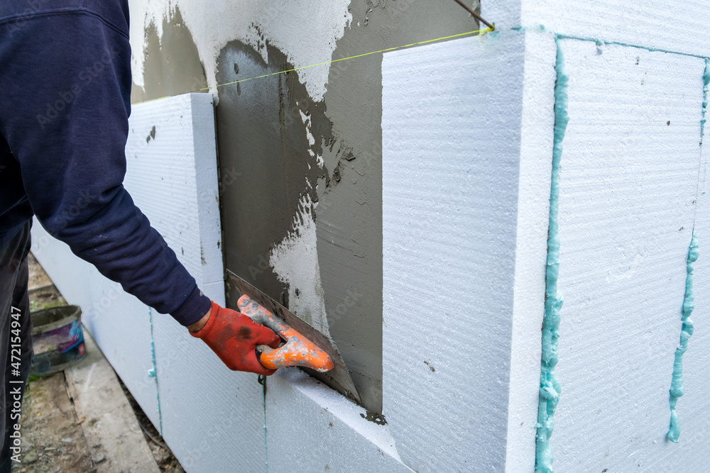 Construction worker installing styrofoam insulation sheets on house ...