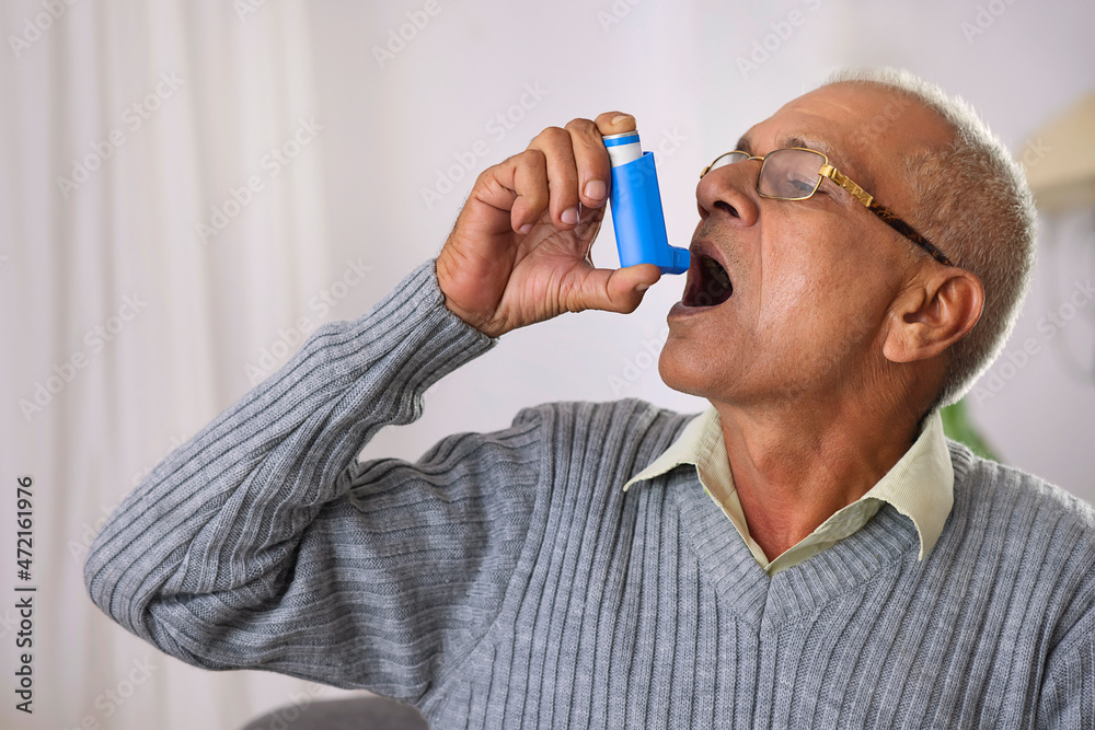 Old age man using her Asthma Inhaler at home Stock Photo | Adobe Stock