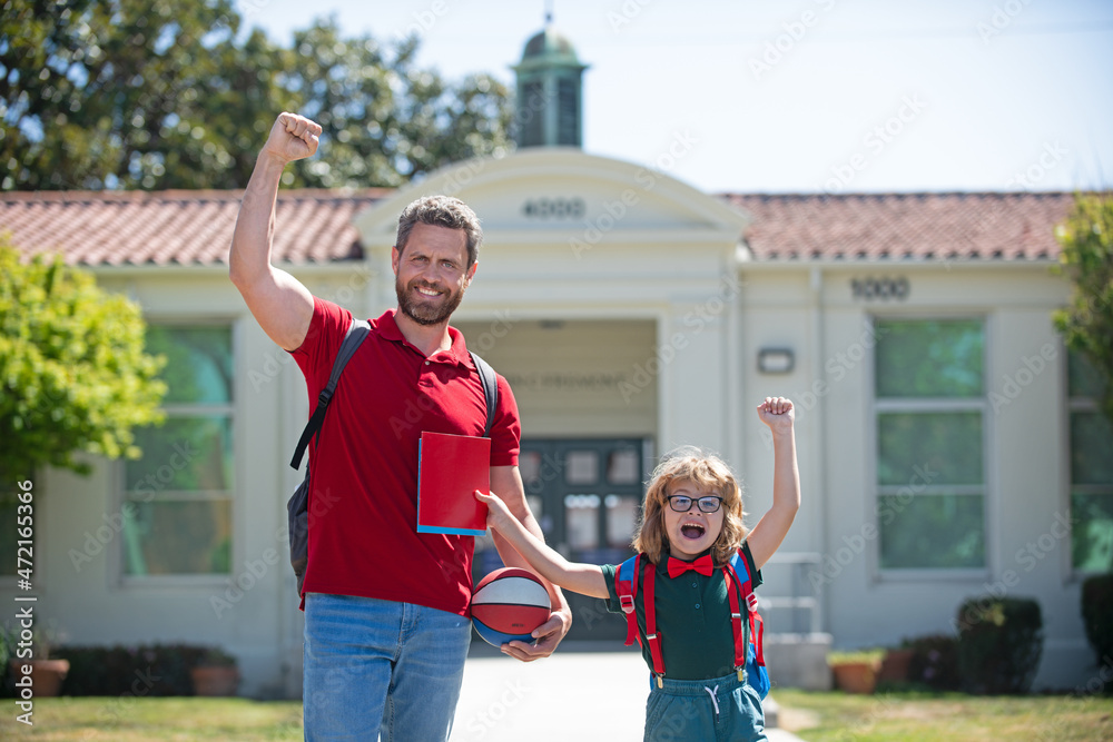 Portrait of cheerful dad and son in front of school in good mood. Happy ...