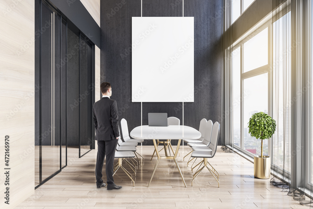 Businessman standing in modern meeting room office interior with empty ...