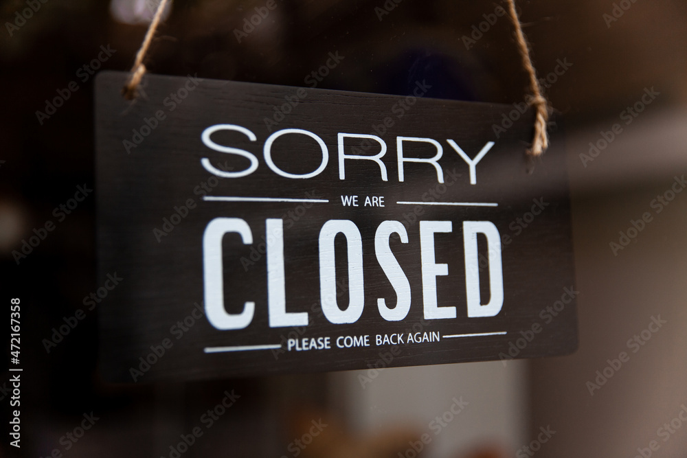 Sorry we are closed sign board hanging on glass door of cafe or store ...