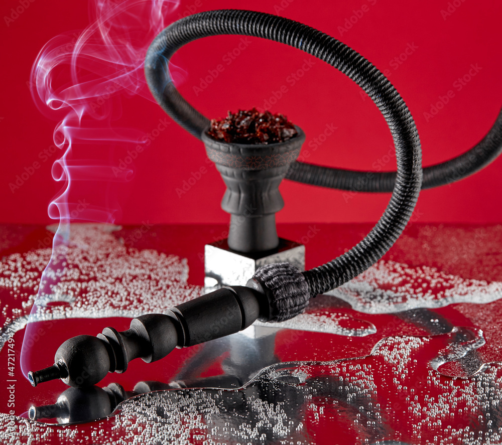 Shisha in a black ceramic cup with an ornament, around which a hookah ...