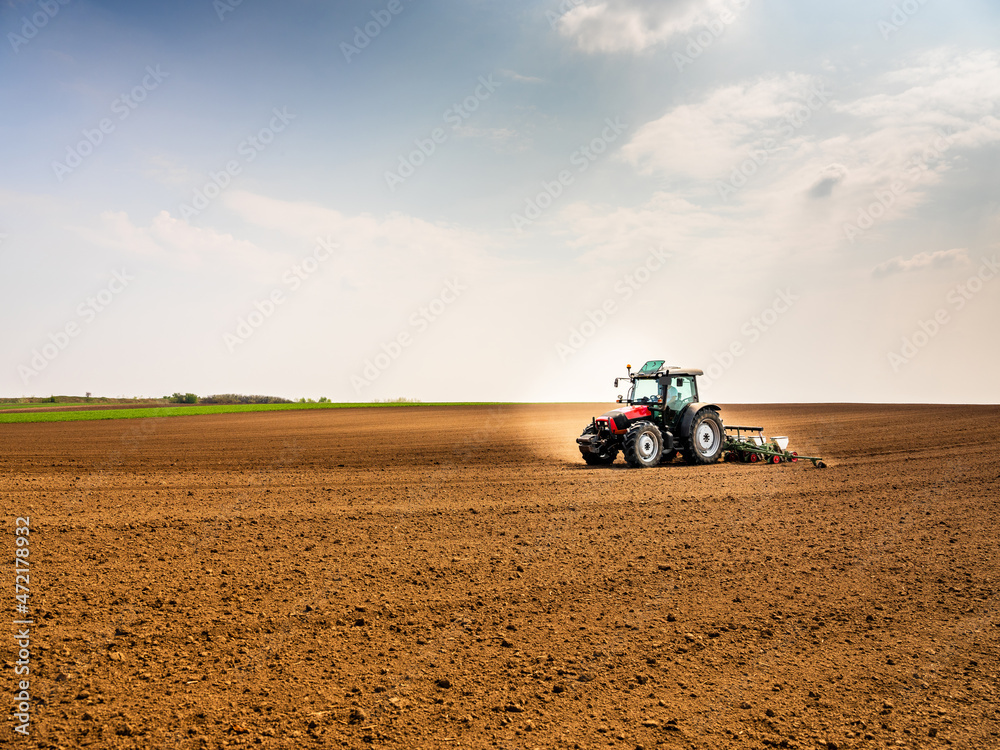 Tractor drilling seeding crops at farm field. Agricultural activity ...