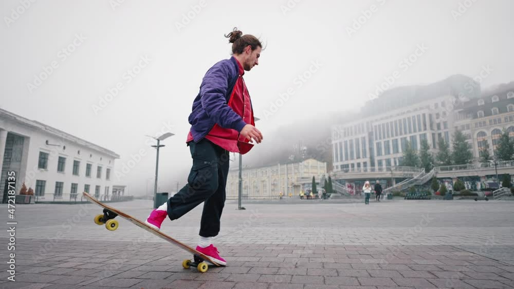 Full length rear view of young man skateboarding while hanging out at ...