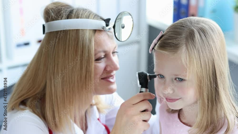 Ent with frontal reflector examining little girl ear using otoscope 4k ...