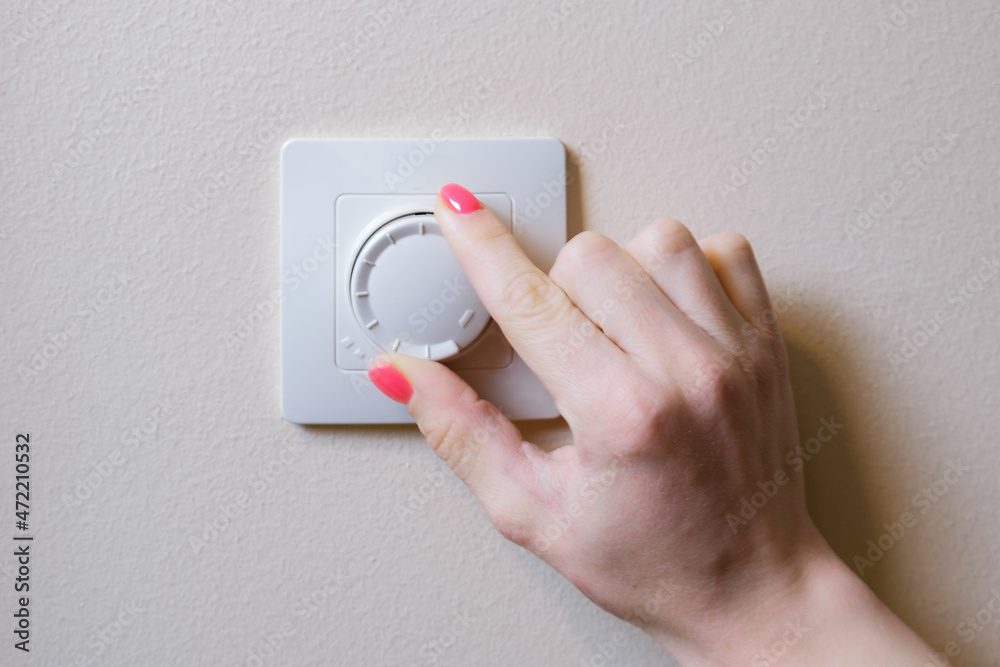 Woman's hand adjusts the lighting with a dimmer lever. An electronic ...