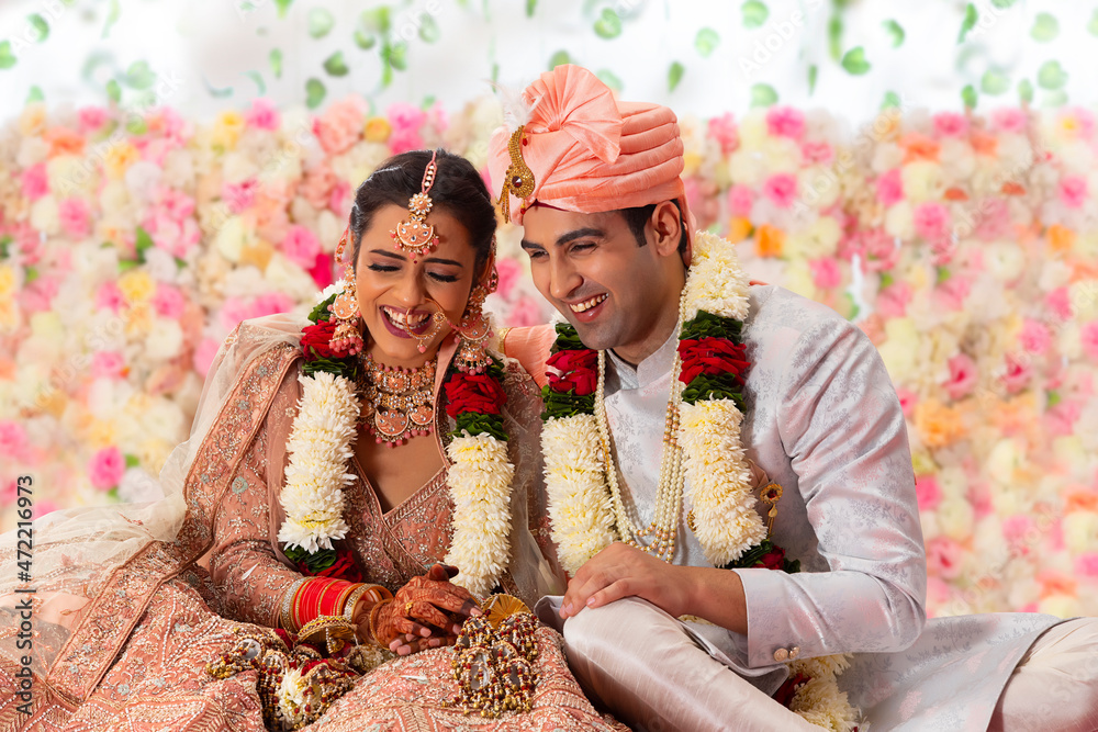 Portrait of a happy Indian wedding couple sitting together on mandap ...