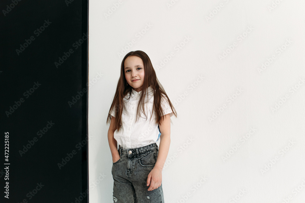 little girl 8 years old, in the studio on a white background, she looks ...