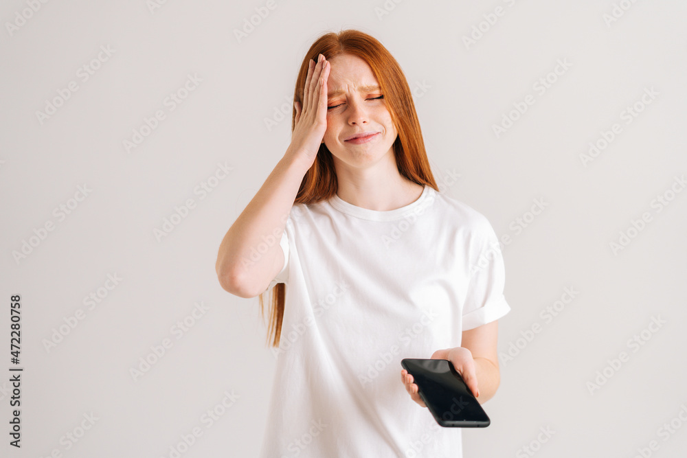 Studio portrait of frustrated young woman reading online message using ...