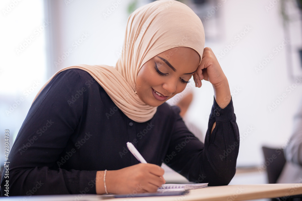 Students taking a test in a classroom. Smart young muslim girls with ...