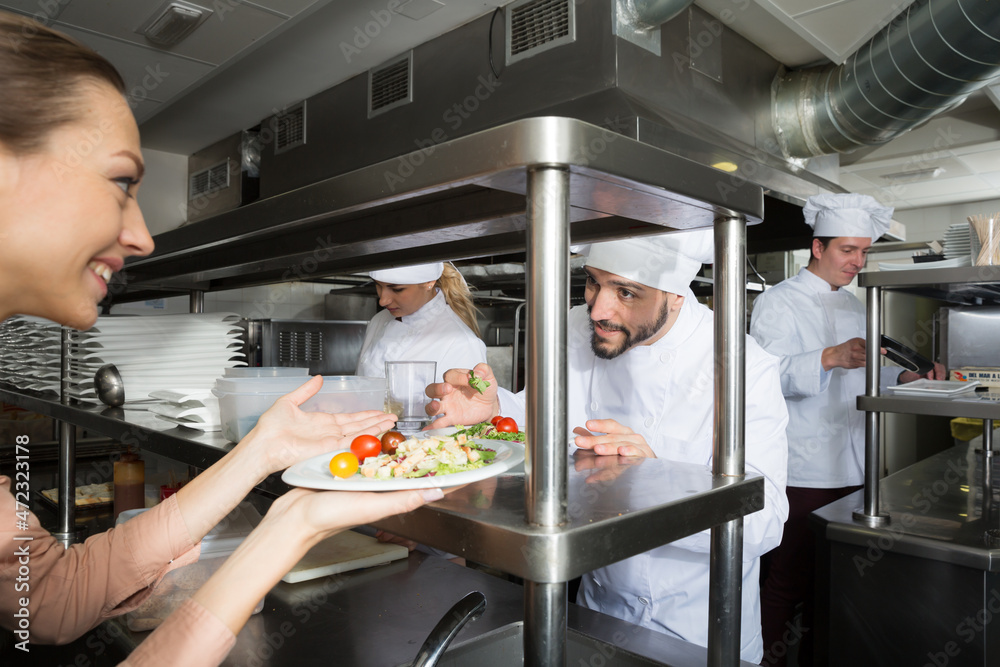 Head chef checking dishes in kitchen of restaurant before serving ...