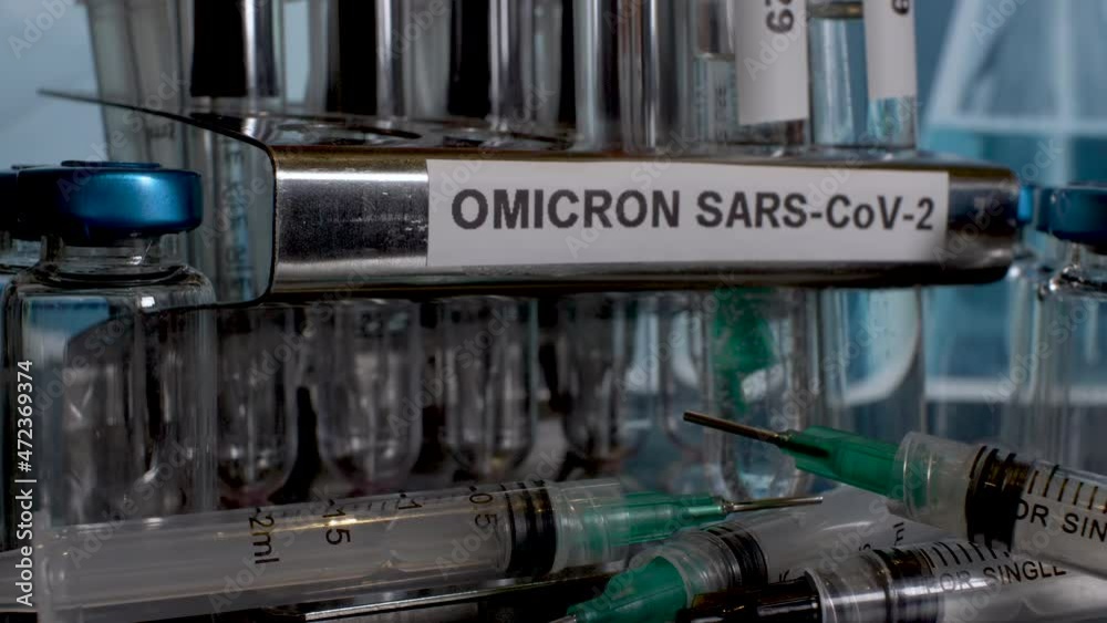 A close look on a metal tube rack labeled OMICRON SARS-CoV-2. The glass ...