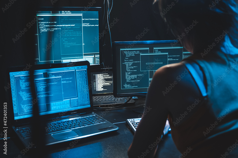 Software developer freelancer woman female work with program code on wide displays at night ...