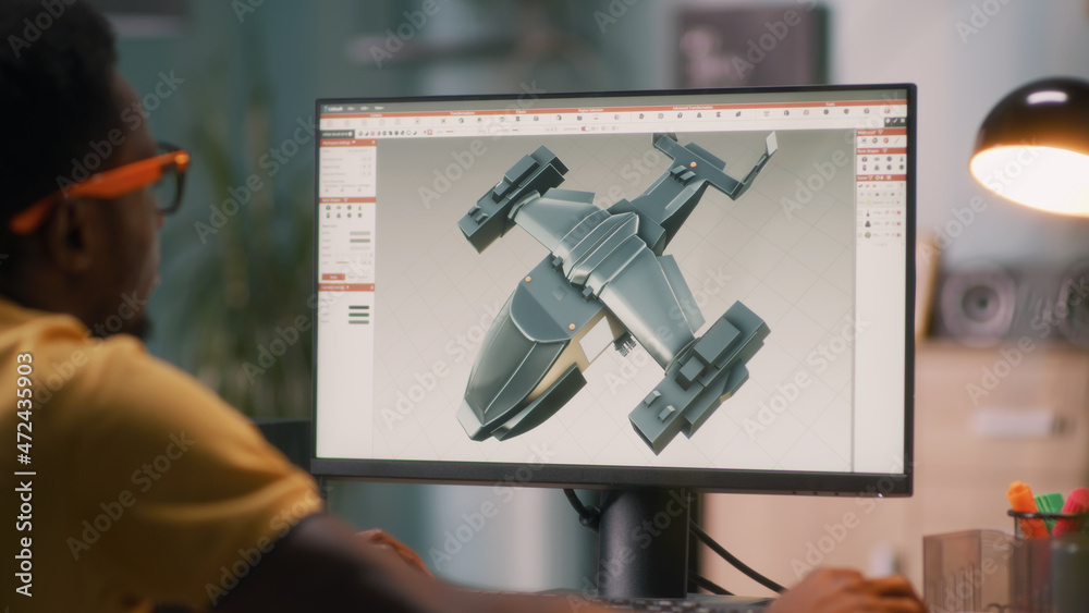Black man using computer and creating 3D model of futuristic aircraft ...