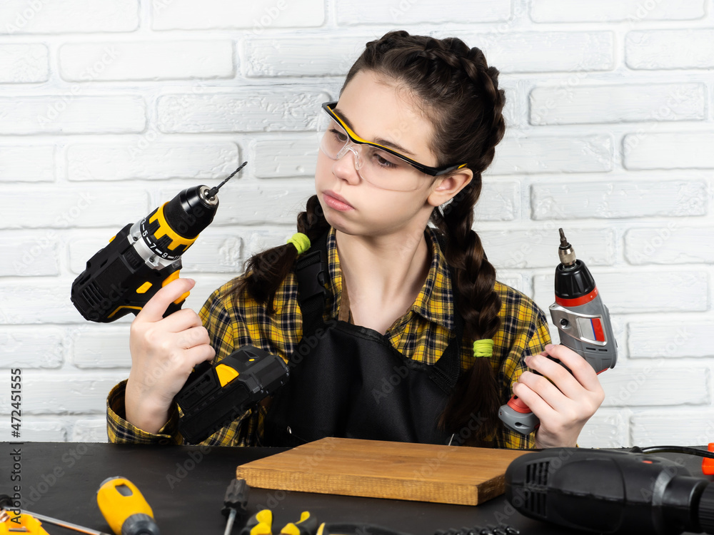 Young teenage girl works with a drill. Working environment in a ...