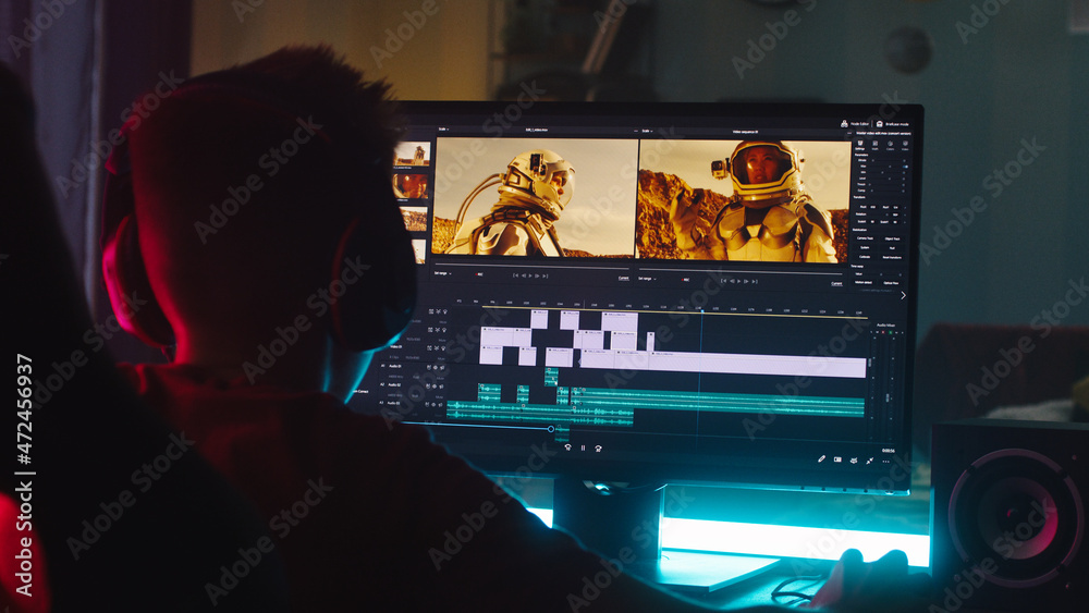 Teenager using computer to edit footage while sitting at desk in ...