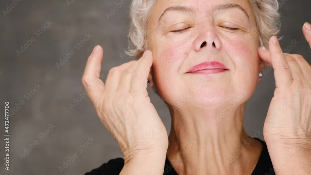 Happy 60s middle aged mature woman touching facial skin looking at ...