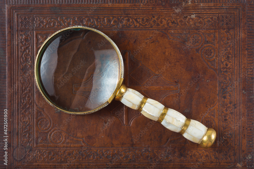 Magnifying glass on ancient bible cover. Old leather-bound book cover ...
