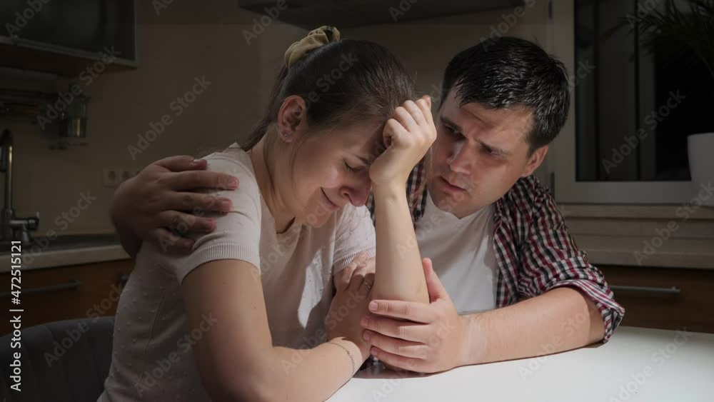 Upset and stressed woman crying and hugging her husband on kitchen at ...