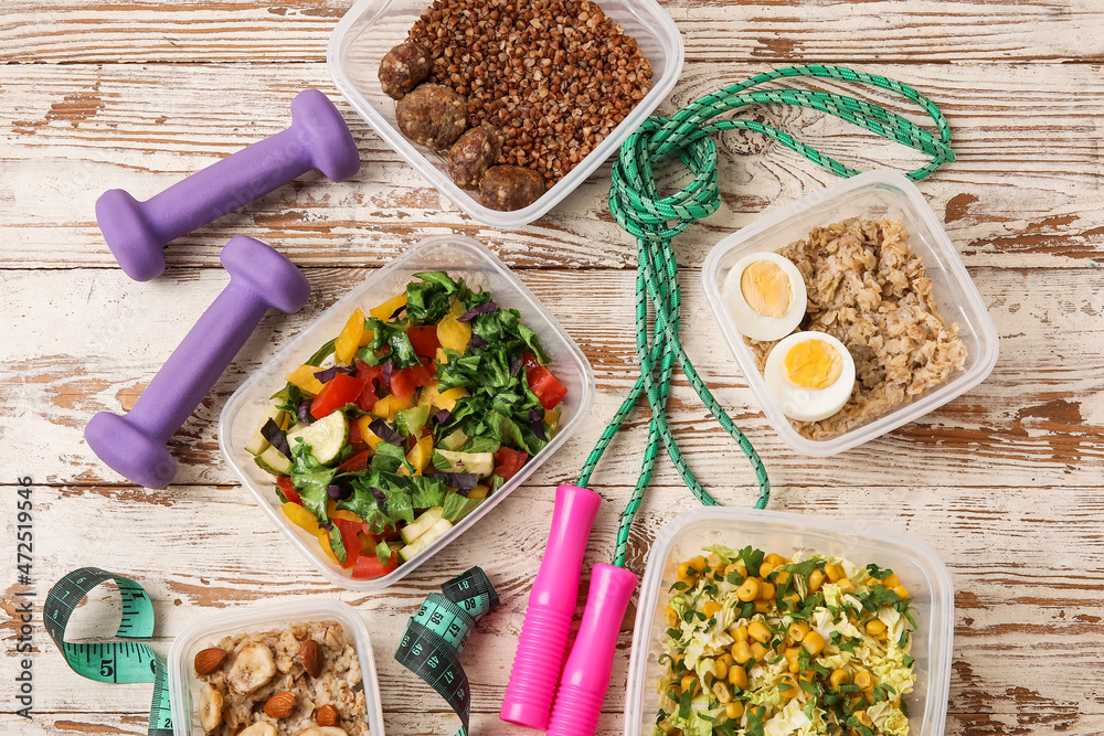 Different healthy food in containers, dumbbells, skipping rope and ...