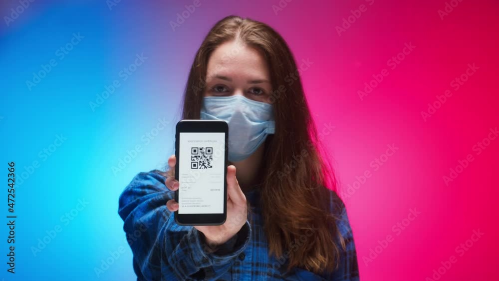 Woman wearing medical mask showing on phone vaccination passport with ...