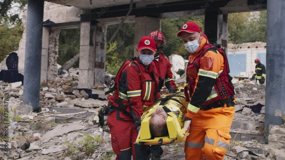 Tracking shot of multiracial men in paramedic uniform carrying survival ...