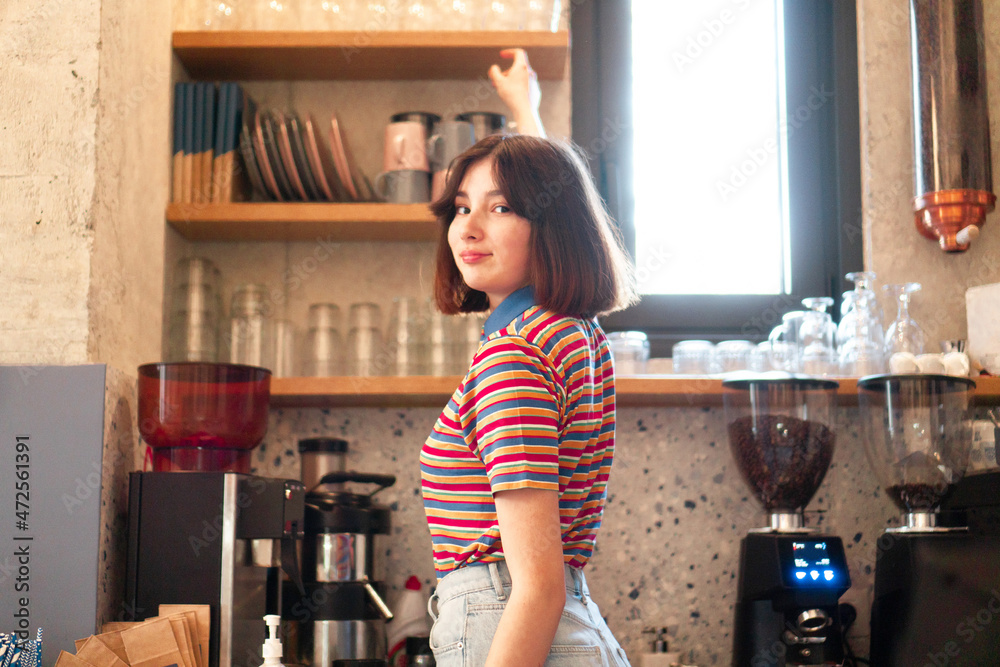 A cute bar waitress is working behind the bar counter with a smile on ...