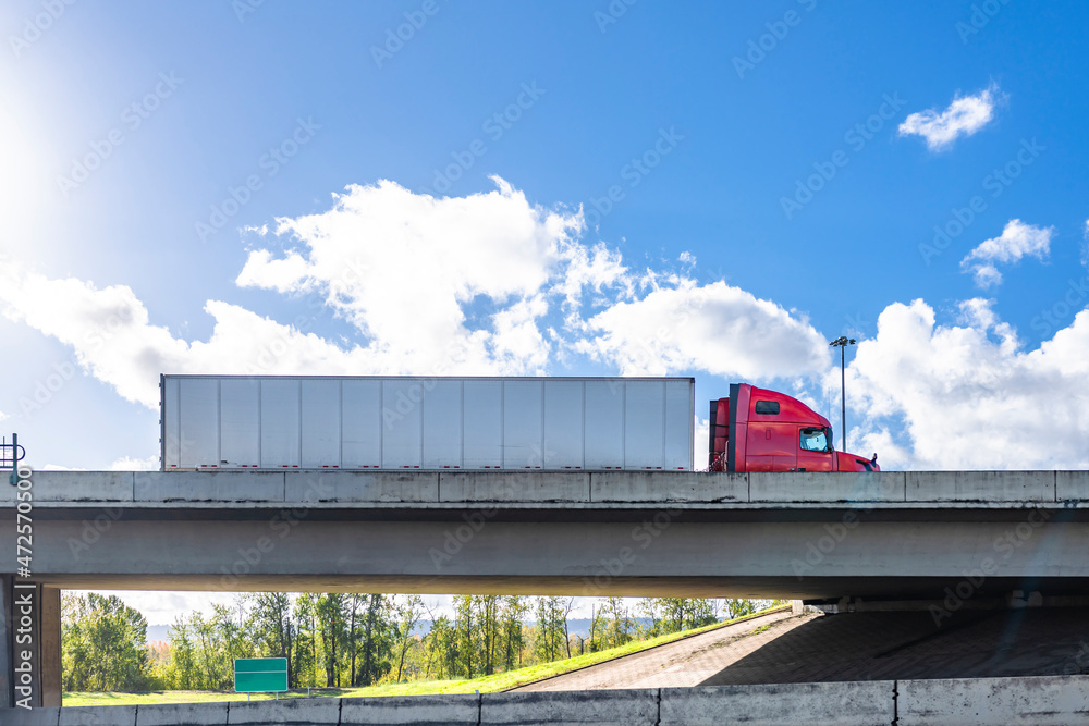 Red big rig semi truck with dry van semi trailer running on the bridge ...