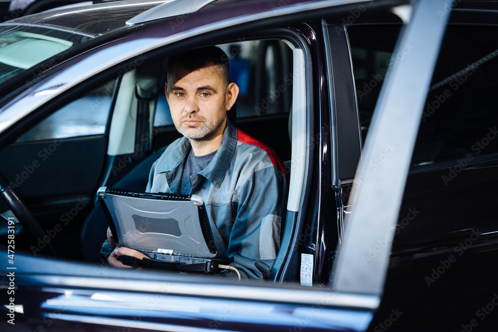 Car service, repair, maintenance concept. Male engineer sitting inside ...