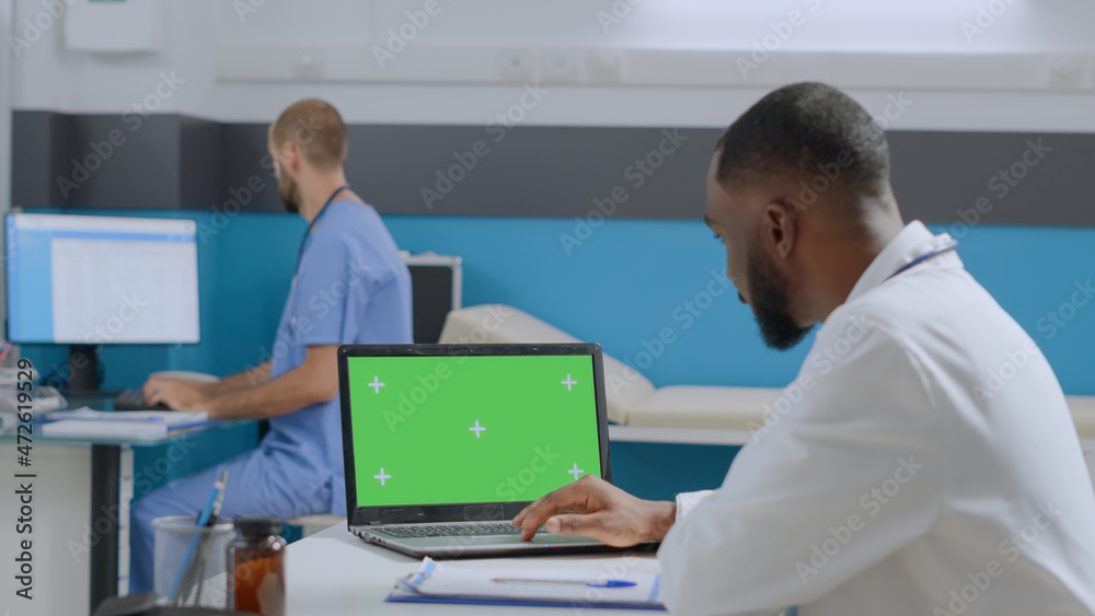 African american physician doctor looking at mock up green screen ...