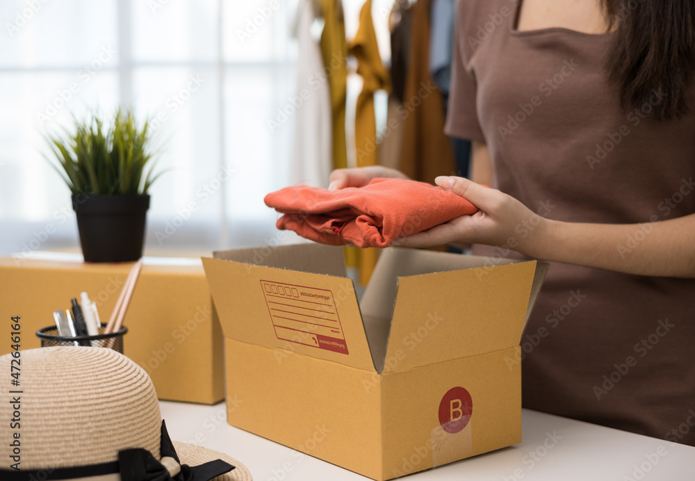 Woman business owner at fashion store packing clothing in the paper bag ...