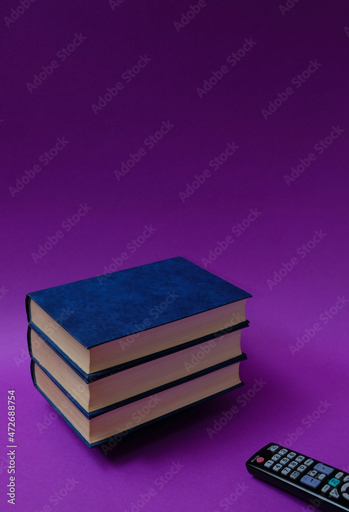 Books, blue covers, stacked on top of each other and a remote control ...