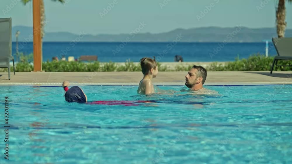 A young woman wearing a hijab swimsuit is swimming in the pool with her ...