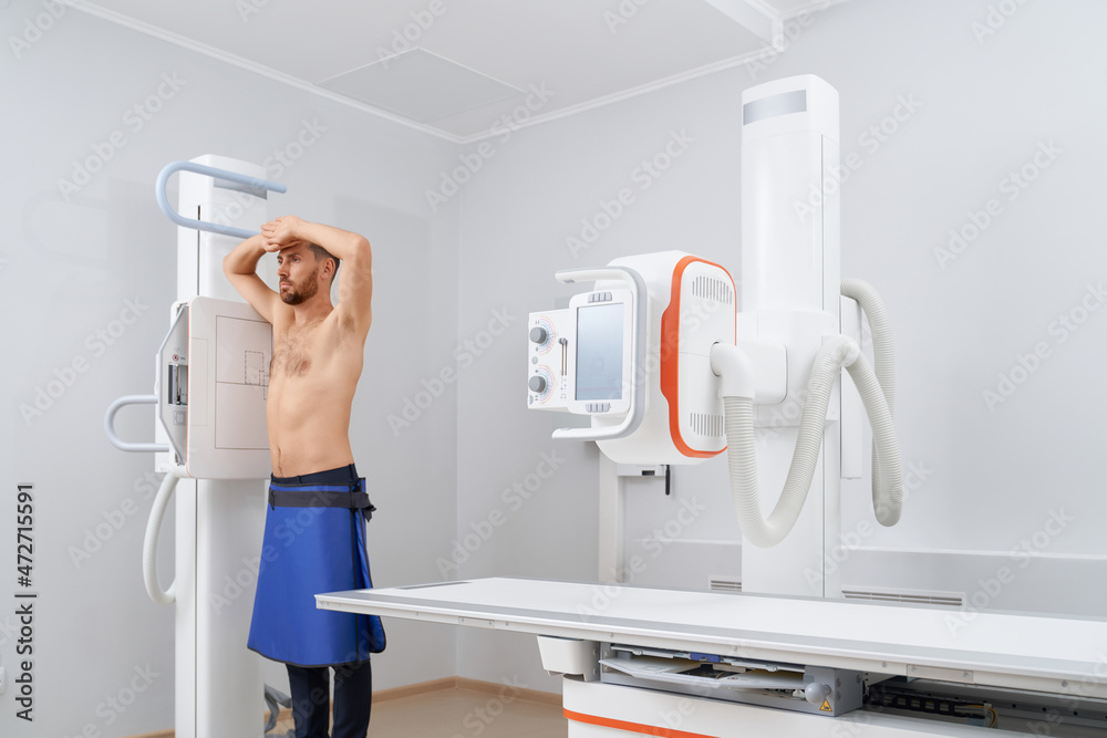 Back view of bared male turned at side scanning lungs in cabinet of ...