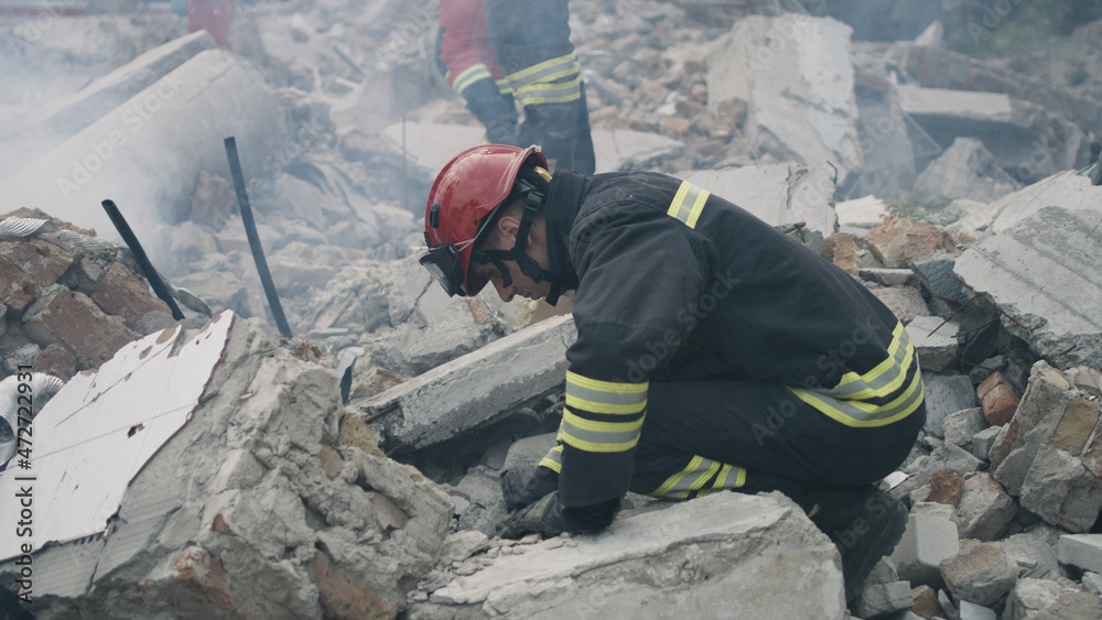 Pan left view of male emergency workers removing concrete rubble in ...