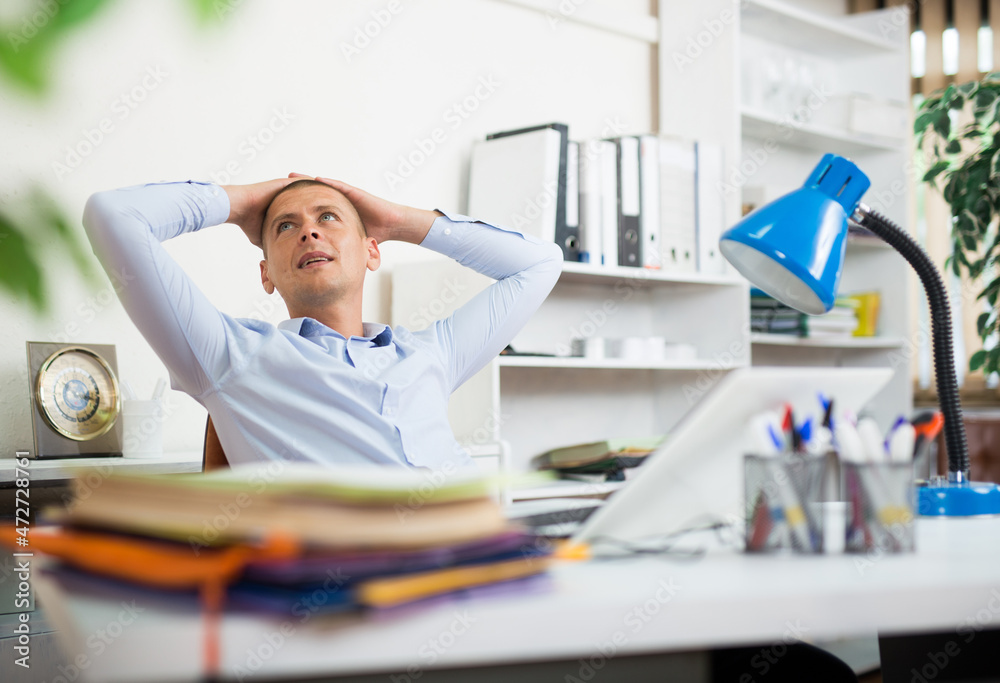Relaxed office worker sitting at workplace, distracted from working on ...