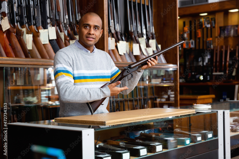 Portrait of hispanic salesman showing collectible old rifled musket on ...