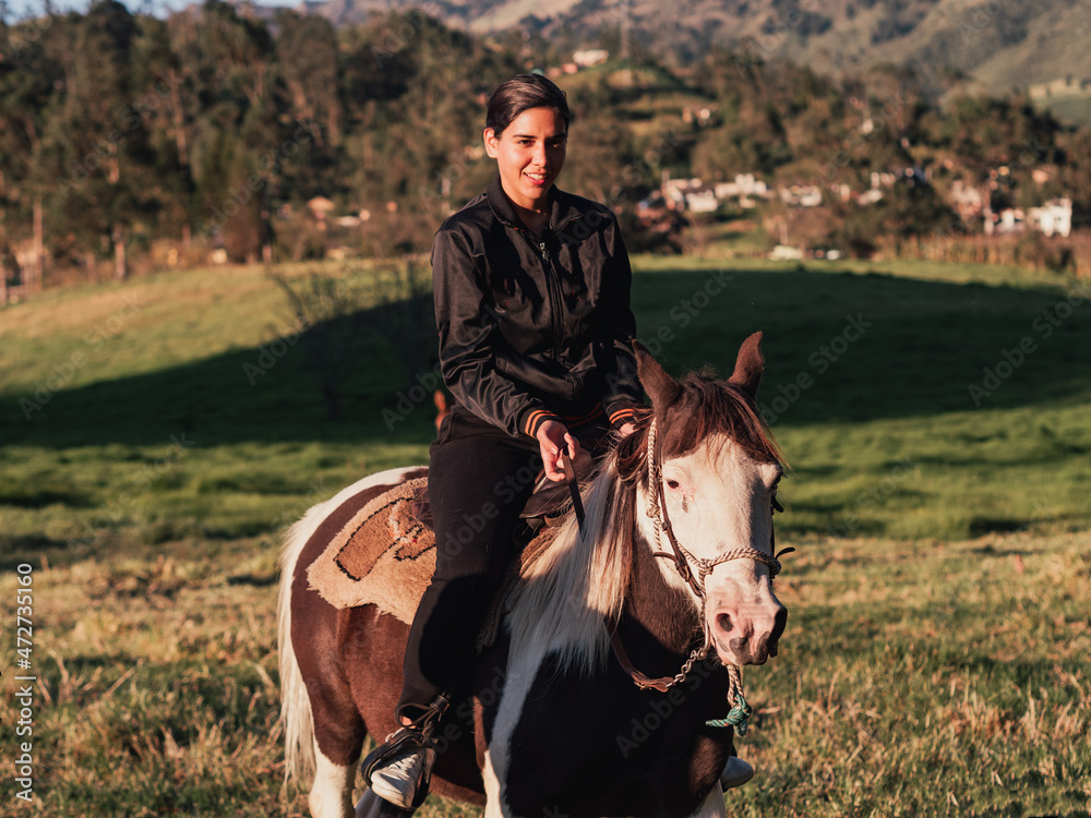 Latin girl rides a horse in a green field at sunset of the day Stock ...