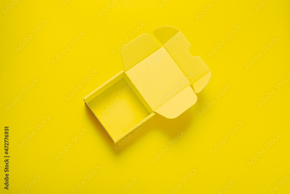 Simple yellow cardboard box on color background, opened, empty inside ...