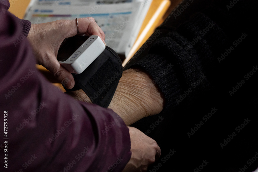 Middle-aged home nurse removing a blood pressure monitor from an ...