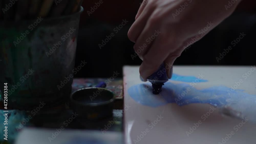 Close-up hands of unrecognizable female artist squeezing paint from ...