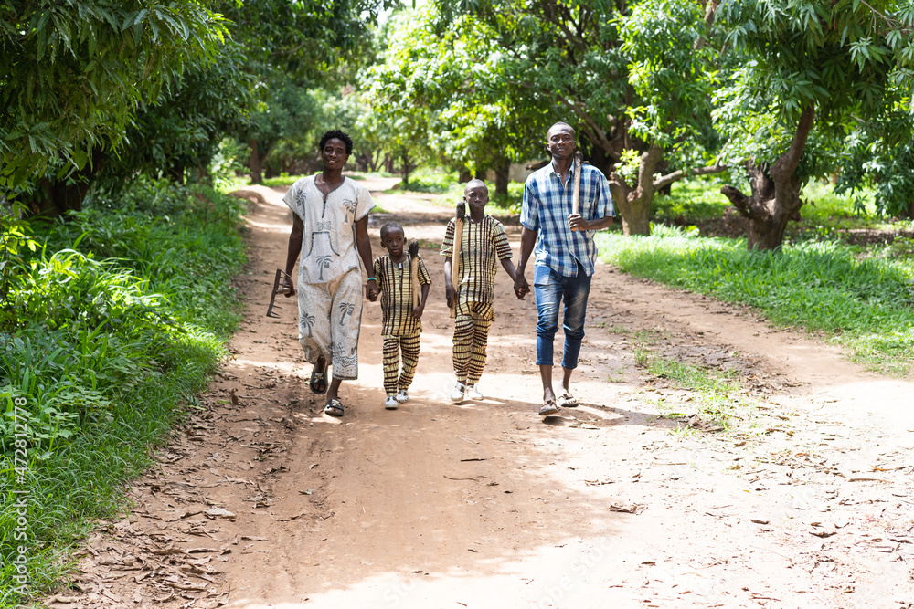 Four young black Africans with rakes and hoes slowly returning home to ...
