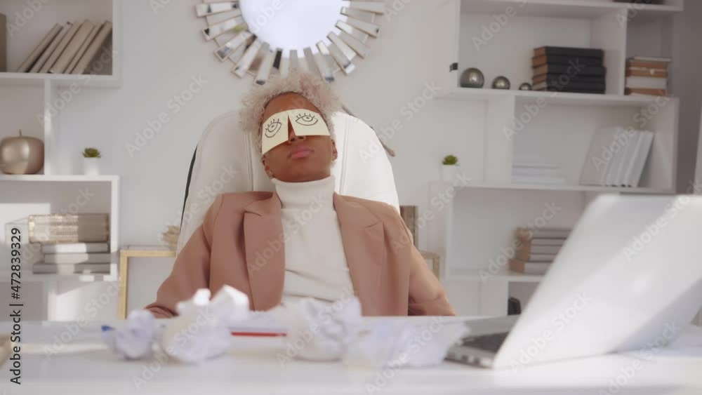 Tired African American businesswoman with memo notes on eyes napping in ...